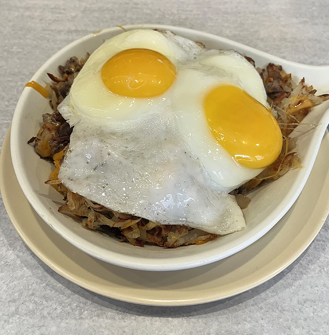 Sunny-side up eggs perched atop a mountain of hash browns &ndash; breakfast architecture that would make Frank Lloyd Wright weep with joy.