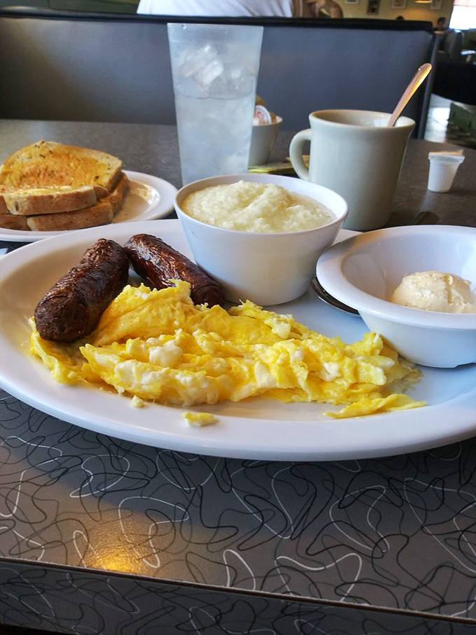 Breakfast perfection on a plate: fluffy scrambled eggs, savory sausage links, and grits that would make any Southerner nod in approval.