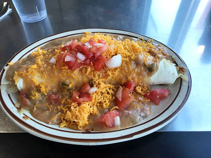 Behold the breakfast burrito in its natural habitat—smothered in green chili and topped with enough cheese to make Wisconsin proud.