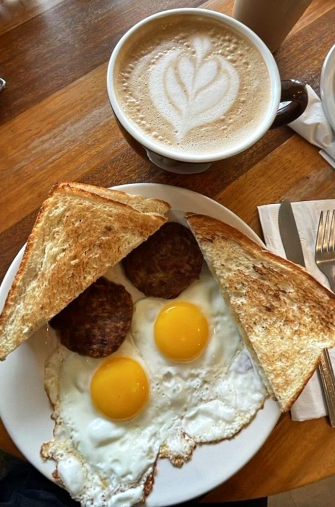 Sunny-side up eggs with perfectly browned sausage patties and golden toast&mdash;the breakfast equivalent of winning the lottery on a Tuesday morning.