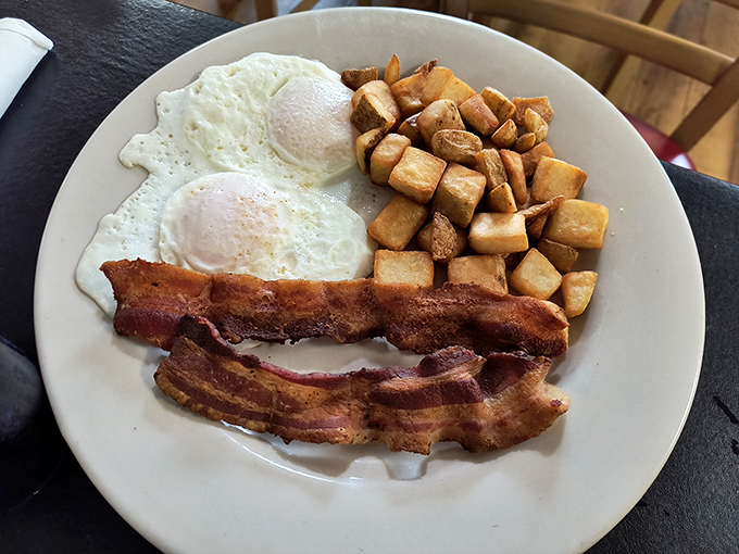 Breakfast perfection on a plate: eggs with just-right runny yolks, bacon with that ideal crisp-to-chew ratio, and home fries that'll haunt your dreams. 