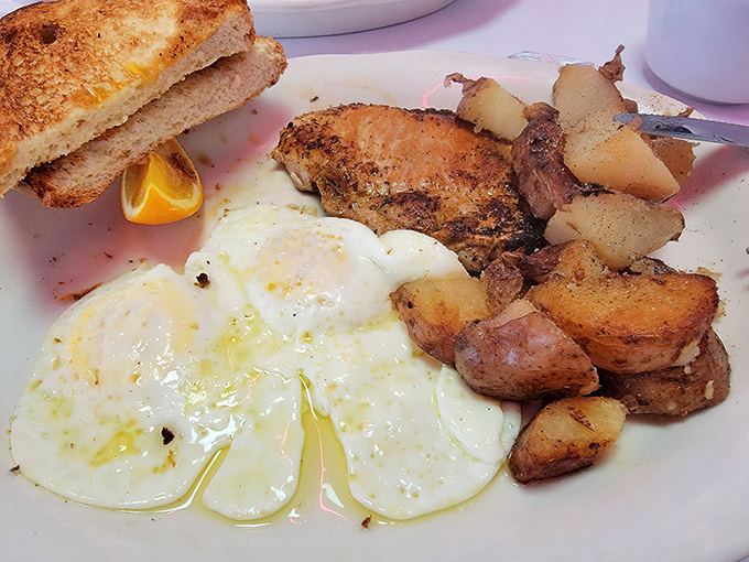 Sunny-side up eggs glisten beside golden home fries and perfectly browned toast—the holy trinity of breakfast done right.