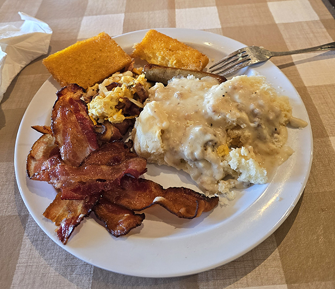 Behold the breakfast of champions! Crispy bacon, cornbread, and eggs smothered in sausage gravy&mdash;a plate that says "diet starts tomorrow."