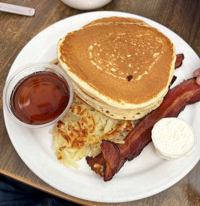 A breakfast platter with pancakes golden as a California sunset, bacon that's achieved crispy perfection, and hash browns worthy of their own fan club.