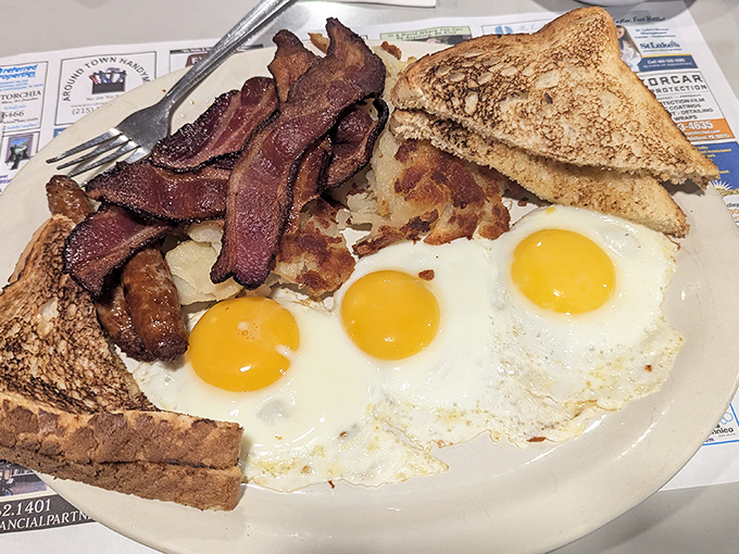 Two eggs staring back like sunny side up emojis, surrounded by enough bacon to make a cardiologist nervous.