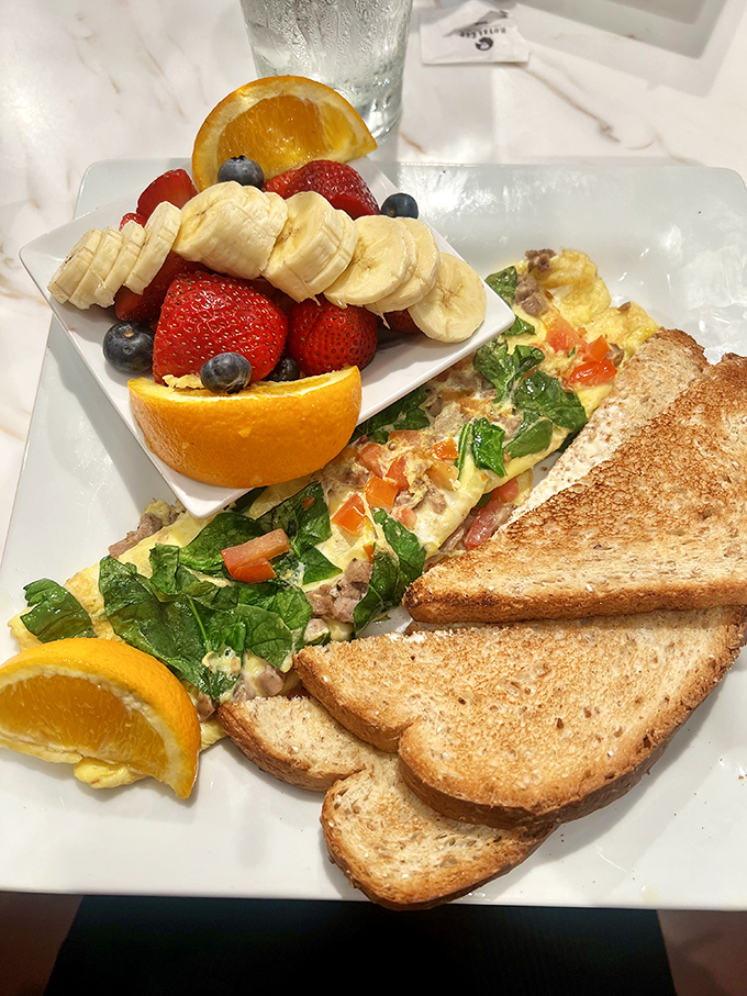 Breakfast artistry at its finest &ndash; a perfectly folded omelet alongside a fruit medley so fresh it looks like it's posing for its Instagram debut.