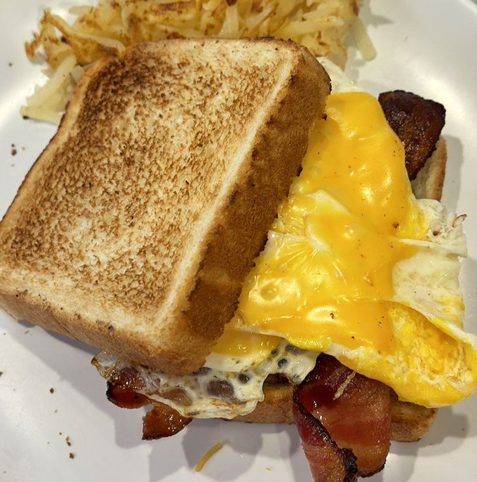 Breakfast architecture at its finest&mdash;perfectly toasted bread supporting a glorious stack of egg, cheese, and bacon. The home fries are just showing off.