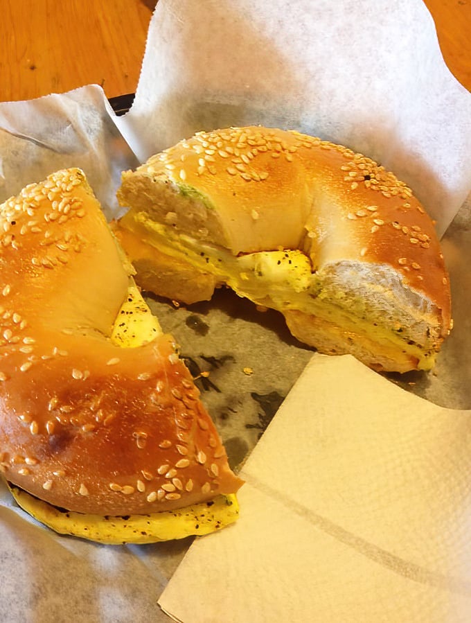 Golden-brown sesame bagel embracing fluffy eggs—a simple pleasure that somehow tastes infinitely better when ocean spray mingles with breakfast steam.