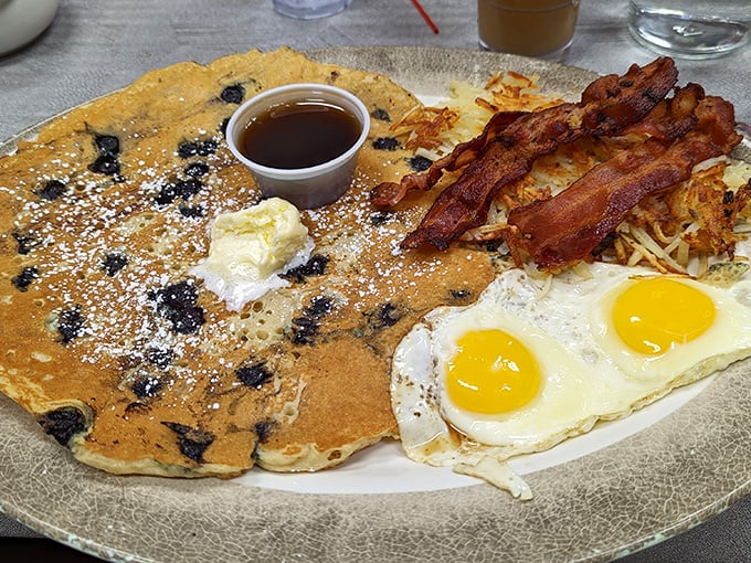 Behold the breakfast trifecta: golden blueberry pancakes, sunny-side-up eggs, and perfectly crisp bacon. The holy trinity of morning indulgence that makes waking up worthwhile.