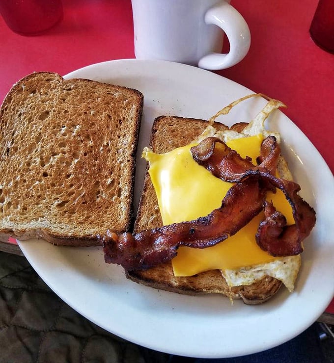 Behold the breakfast sandwich in its natural habitat: melted cheese cascading over crispy bacon on perfectly toasted bread. Poetry on a plate.