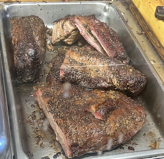 Behold the brisket in its natural habitat – glistening with a pepper-crusted bark that's earned through hours of patient smoking and BBQ wisdom.