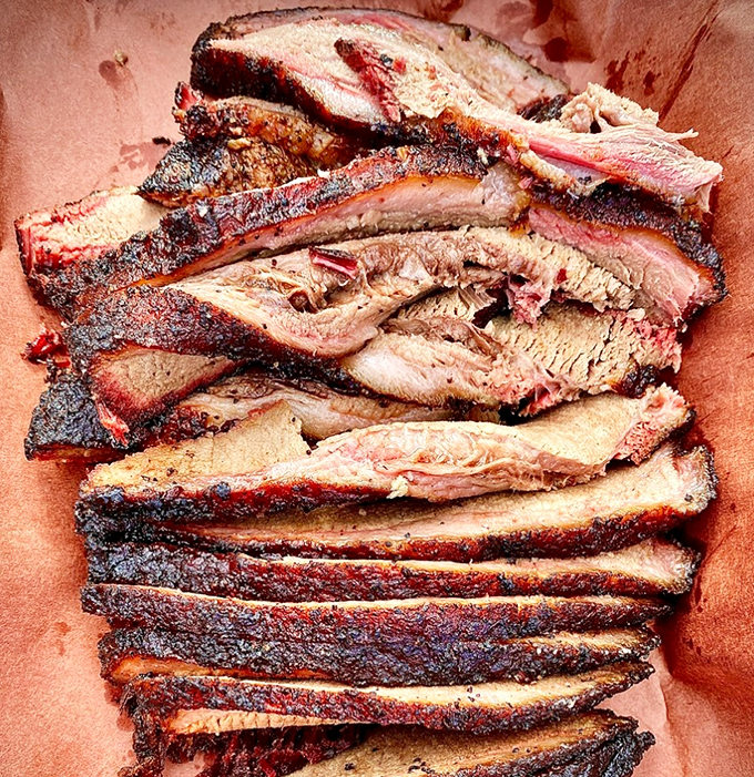 Brisket slices fanned out like a smoky deck of cards, each one promising a full house of flavor with that telltale pink smoke ring.