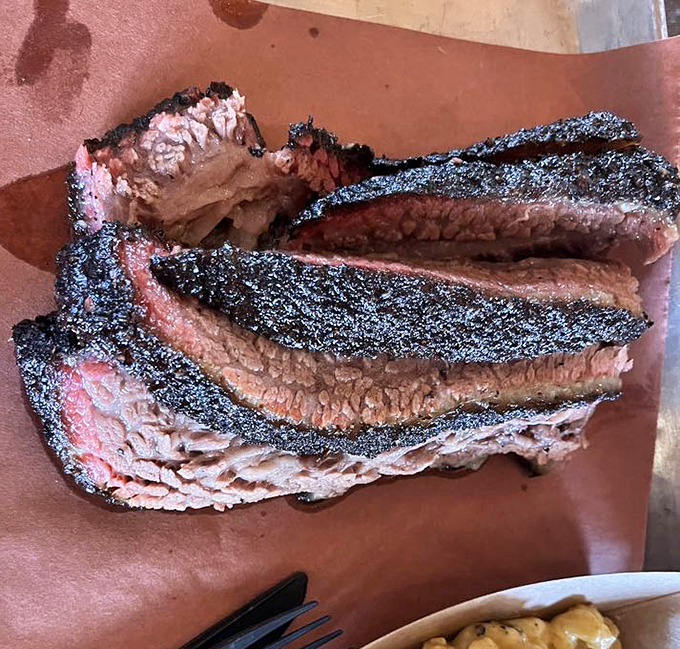 Behold the brisket – that dark bark, that pink smoke ring, that juicy interior. This isn't food; it's edible poetry.