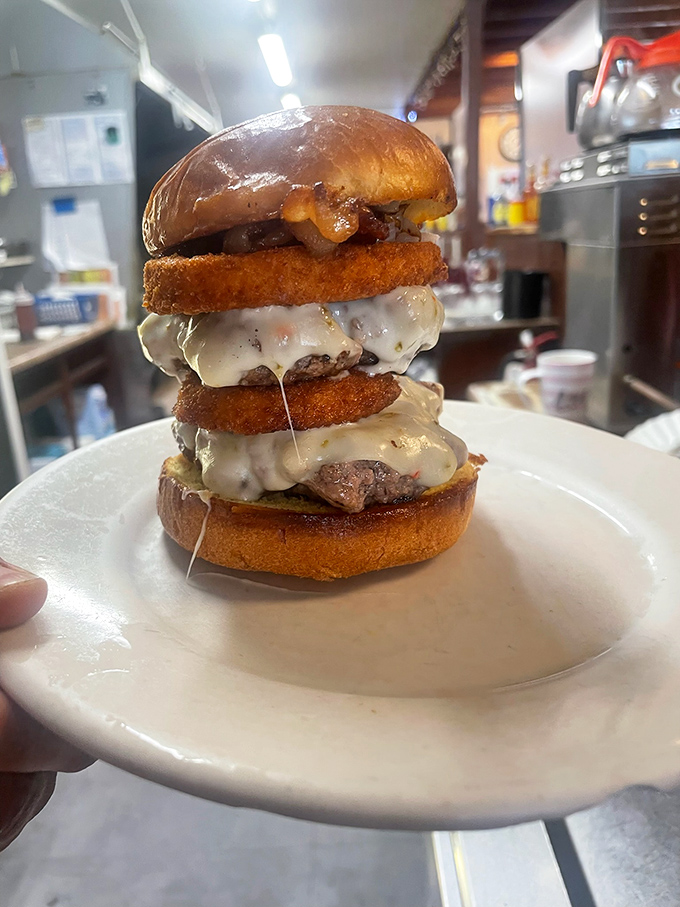 This towering burger masterpiece defies gravity and common sense, but who's complaining about that cheese cascade?
