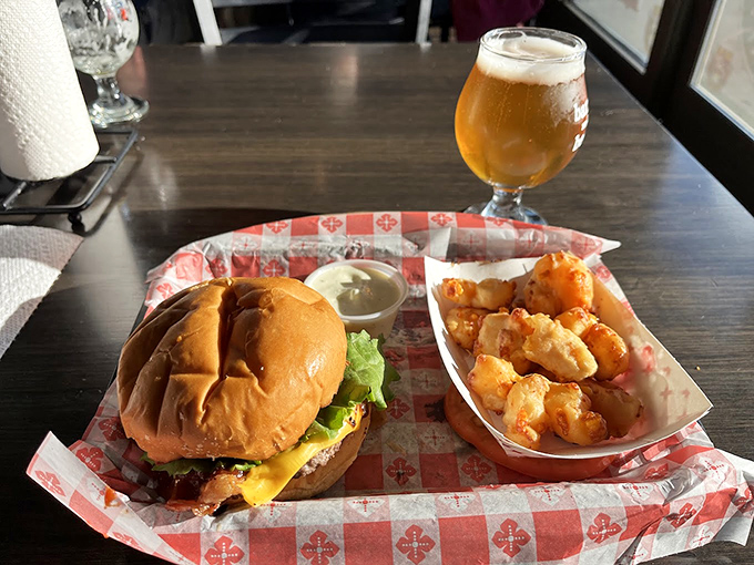 A classic cheeseburger stands at attention next to golden cheese curds, while a craft beer waits patiently to complete this holy trinity of indulgence.