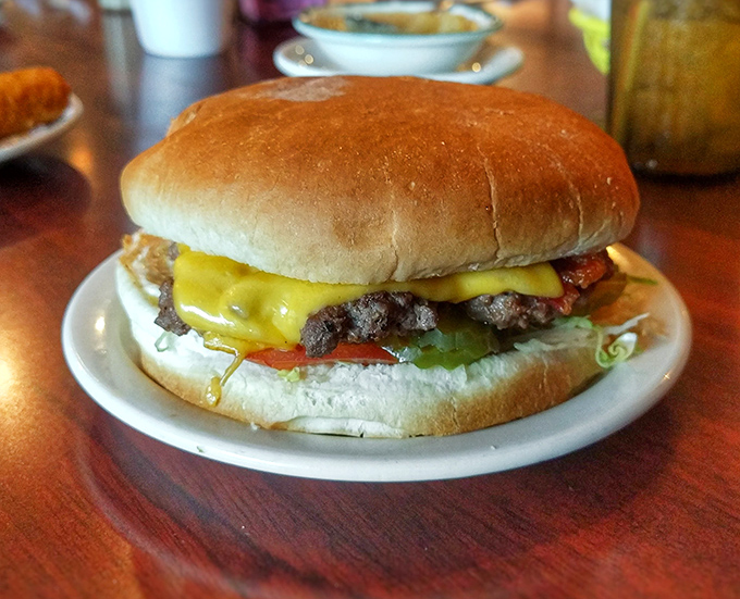 Behold the star attraction: a perfectly proportioned burger where cheese cascades over the patty like a yellow waterfall of happiness.