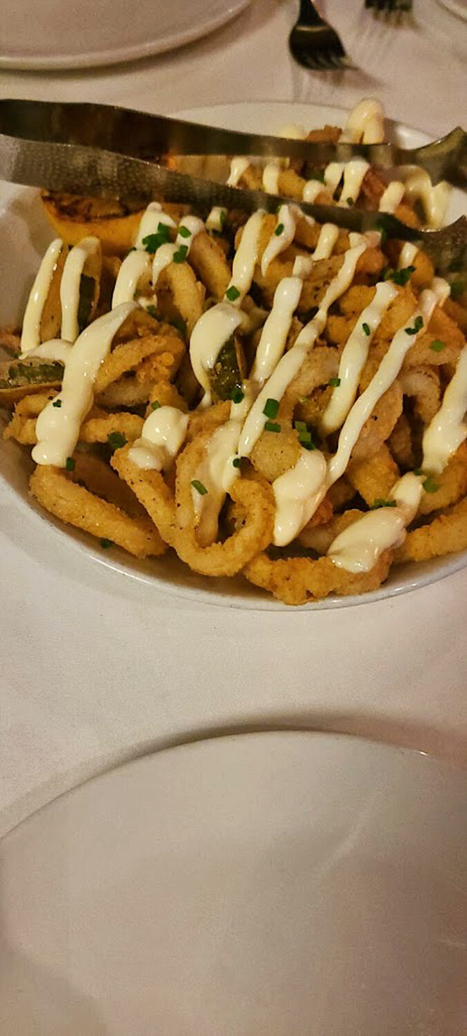 The calamari arrives like the prom king&mdash;golden, perfectly dressed, and surrounded by an adoring court of sauce. This isn't bar food; it's a revelation.