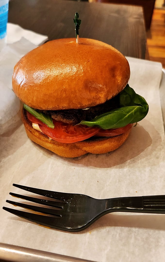 This isn't just a burger &ndash; it's architecture. The glossy bun, vibrant tomato, and fresh greens create the kind of stackable perfection that demands a moment of silent appreciation.