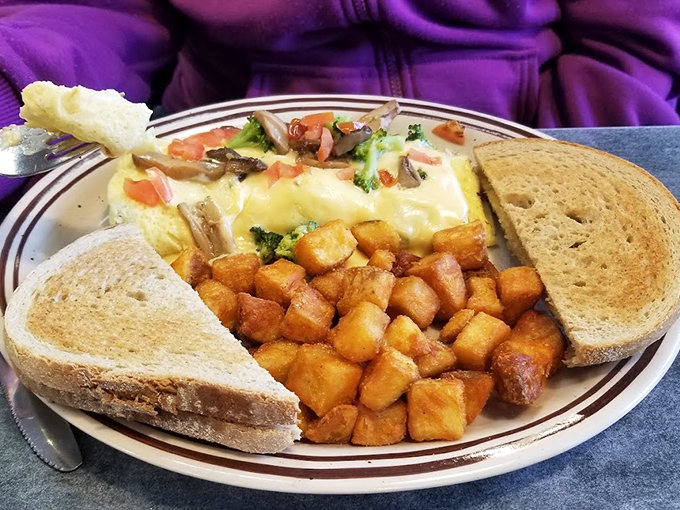 Fork-ready perfection: The Garden Omelet arrives with golden home fries and toast, proving vegetables can party just as hard as bacon when properly introduced to eggs.