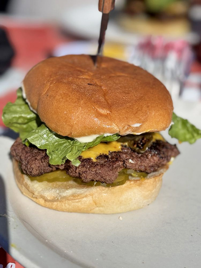 Behold the burger that launched a thousand road trips! This hand-formed patty with melted cheese and fresh toppings is stabbed with a knife&mdash;not for drama, but necessity.