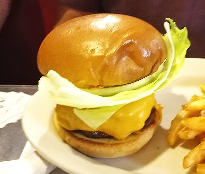 The classic cheeseburger in all its glory: perfectly melted cheese cascading over a substantial patty, with fresh lettuce standing at attention.