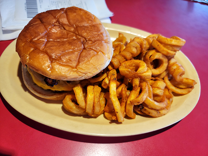 Behold the star of the show: a perfectly grilled cheeseburger with curly fries that puts modern fast food to absolute shame.
