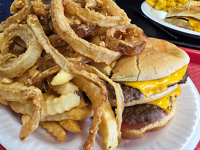 Behold the star of the show: a cheeseburger so magnificent it deserves its own agent, paired with fries and rings that refuse to play supporting roles.
