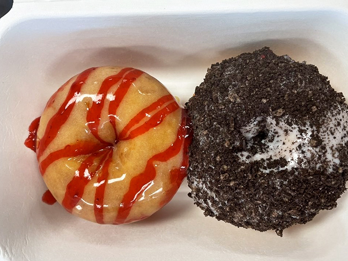 Sweet science in action: a strawberry-drizzled classic alongside what appears to be an Oreo-crusted masterpiece. Two completely different donut personalities sharing one delicious box.