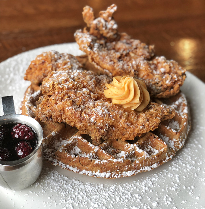 Behold the star attraction: golden-fried chicken perched atop a Belgian waffle throne, dusted with powdered sugar and crowned with butter.