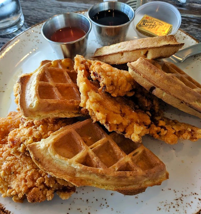 Behold the star attraction: golden-crisp chicken nestled against buttery waffles, with maple syrup standing by like a sweet supporting actor.