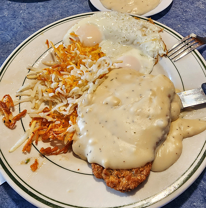 Behold the star attraction: chicken fried steak smothered in peppery country gravy with crispy hash browns. This plate has comforted more souls than a therapist.