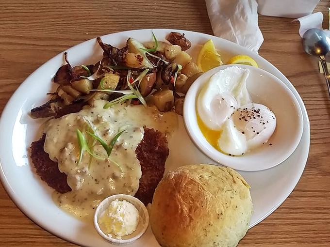 The holy grail of comfort food: golden-brown chicken fried steak smothered in creamy gravy with perfectly cooked eggs and that herb biscuit stealing the show.