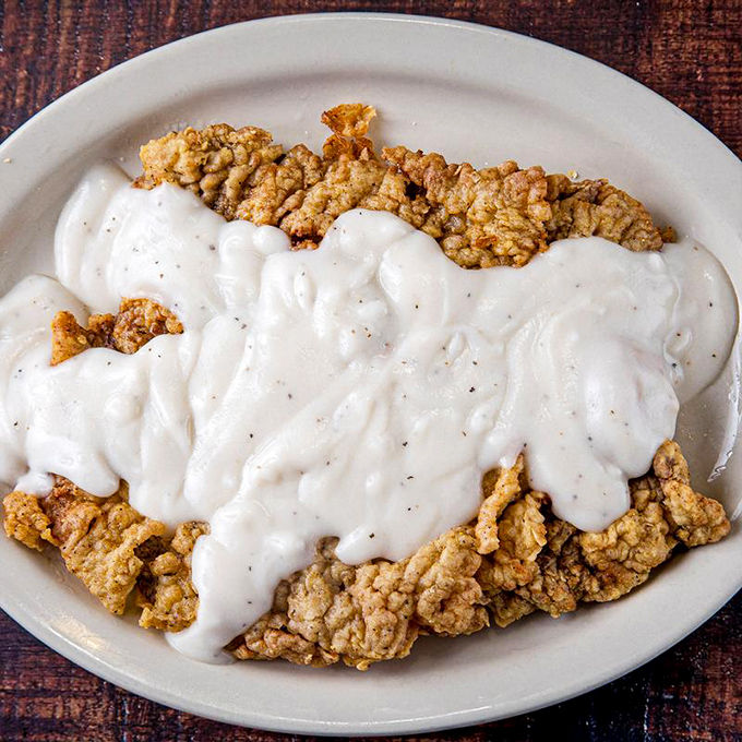 Behold the holy grail of Texas cuisine&mdash;chicken fried steak swimming in creamy pepper gravy that cascades over the edges like a delicious waterfall of Southern comfort.