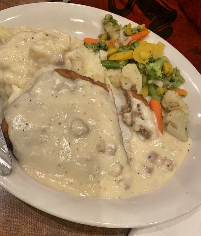Country-fried steak swimming in creamy gravy &ndash; where the crispy exterior gives way to tender meat beneath, like finding an oasis in the desert.