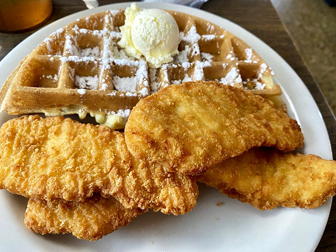 The chicken and waffle plate arrives like breakfast royalty—golden fried chicken beside a powdered waffle with butter melting into those perfect squares.