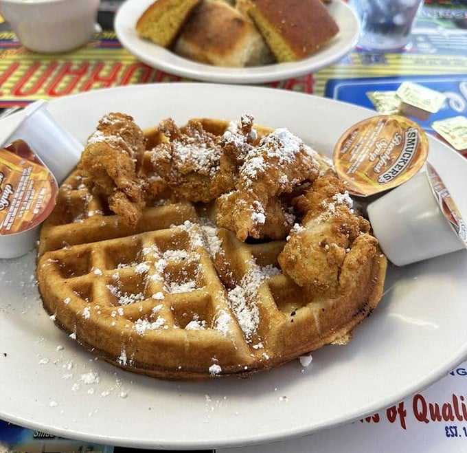 Behold the star attraction: golden-brown chicken perched atop a Belgian waffle dusted with powdered sugar. Sweet meets savory in a dance as old as time.