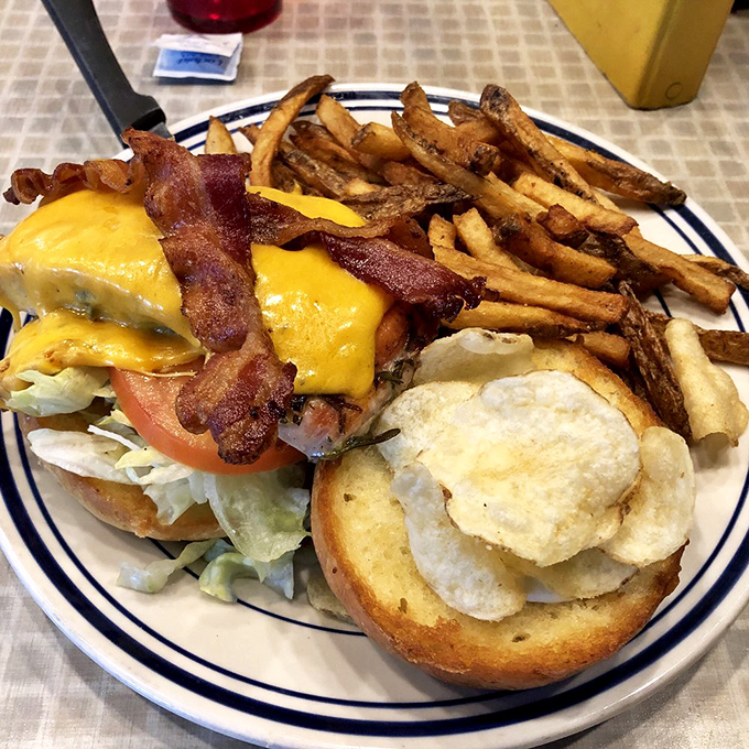 Not just a sandwich, but a monument to excess. Melted cheese cascades over bacon and fresh veggies while crispy fries stand guard.