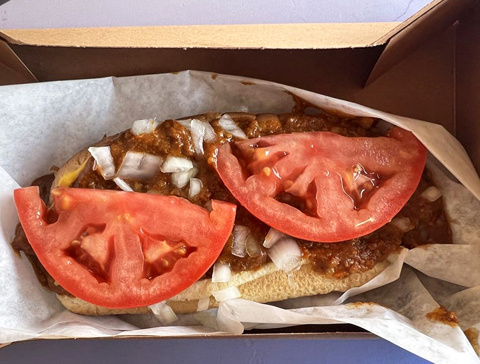 Chili dog perfection in its natural habitat. Those tomato slices aren't just garnish&mdash;they're the cool, fresh counterpoint to that rich, meaty chili blanket.