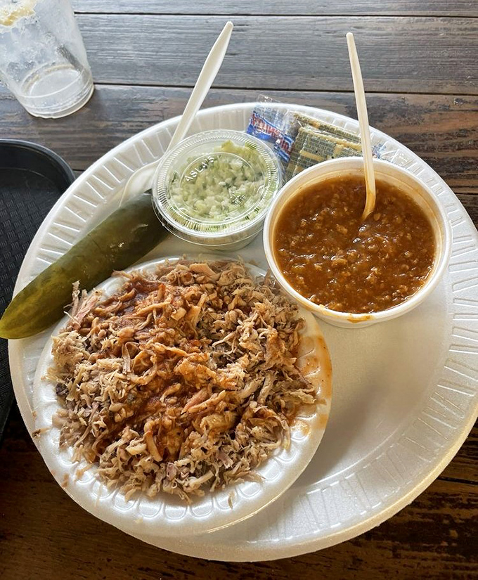 Behold the holy trinity of Southern comfort: chopped pork with that perfect bark-to-meat ratio, Brunswick stew thick enough to stand a spoon in, and a pickle for good measure.