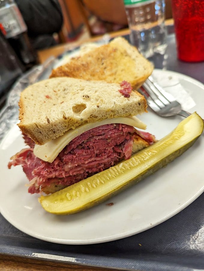 This isn't just a sandwich; it's a skyscraper of thinly-sliced corned beef on rye with a pickle spear standing guard. Architecture you can eat!
