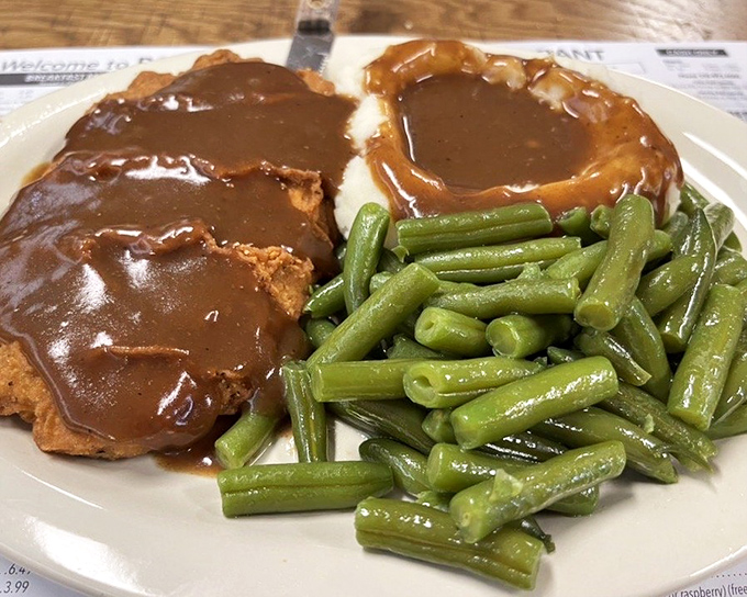 Country fried steak swimming in gravy alongside vibrant green beans—a plate that doesn't just feed your stomach but hugs your soul.
