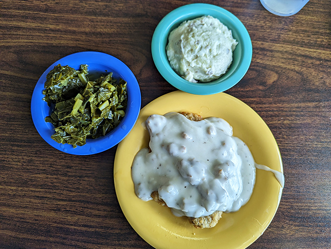 Southern cooking 101: A perfect biscuit drowning in creamy sausage gravy alongside collard greens and mashed potatoes. Cardiologists hate this photo.