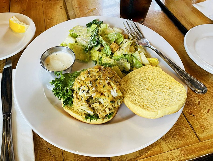 Behold the star of the show: a golden-brown crab cake sandwich that's more crab than cake, served with a side of Caesar salad and maritime dreams.