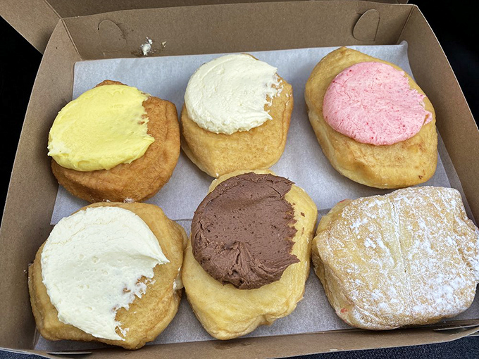 A box of frosted treasures awaits – vanilla, chocolate, strawberry – like edible jewels that make adults feel like kids on allowance day again.