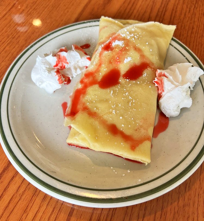 Crepes that strike the perfect balance between delicate and substantial, adorned with strawberry sauce that zigzags with purpose. Whipped cream islands complete this breakfast archipelago.