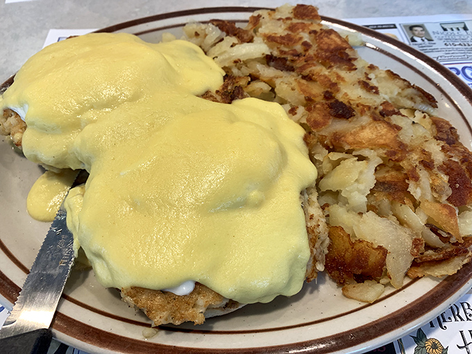 Behold the star attraction: Eggs Benedict draped in hollandaise that's practically liquid sunshine, accompanied by home fries that demand equal attention.