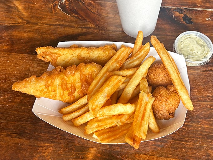 Golden-battered fish rests atop a mountain of crispy fries, with hush puppies standing guard. This isn't just food&mdash;it's edible architecture.