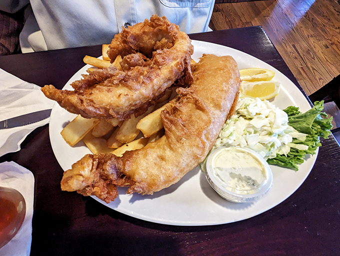 Golden-battered fish that shatters with each bite, alongside chips that achieve the holy trinity of crisp exterior, fluffy interior, and proper heft. This is fish and chips done right.