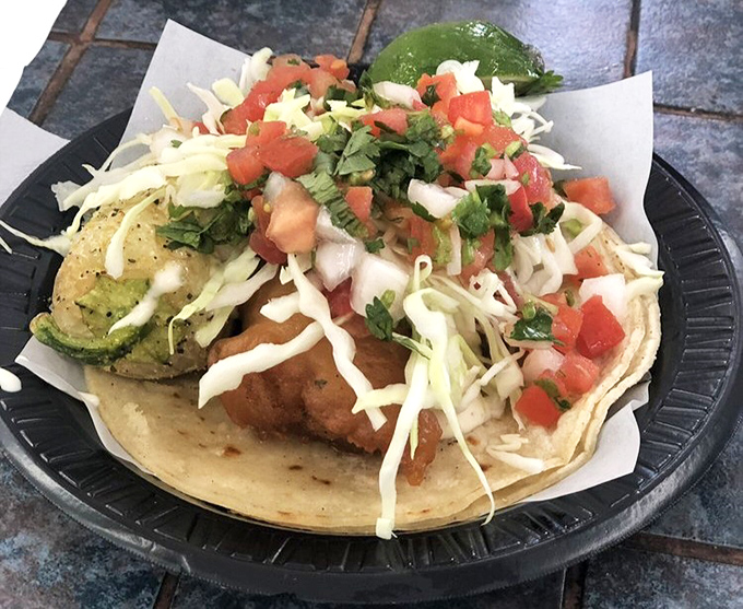 Behold the star attraction: a perfectly battered fish taco adorned with fresh cabbage, pico de gallo, and a slice of lime standing at attention.