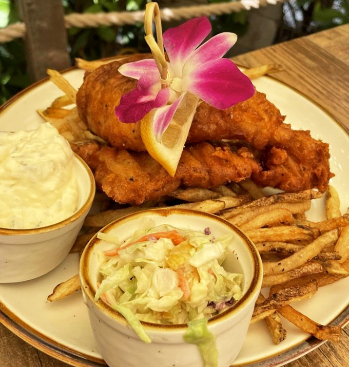 The fish and chips arrive like edible sunshine—golden, crispy, and adorned with a tropical flower that says, "Yes, you're still in Florida."